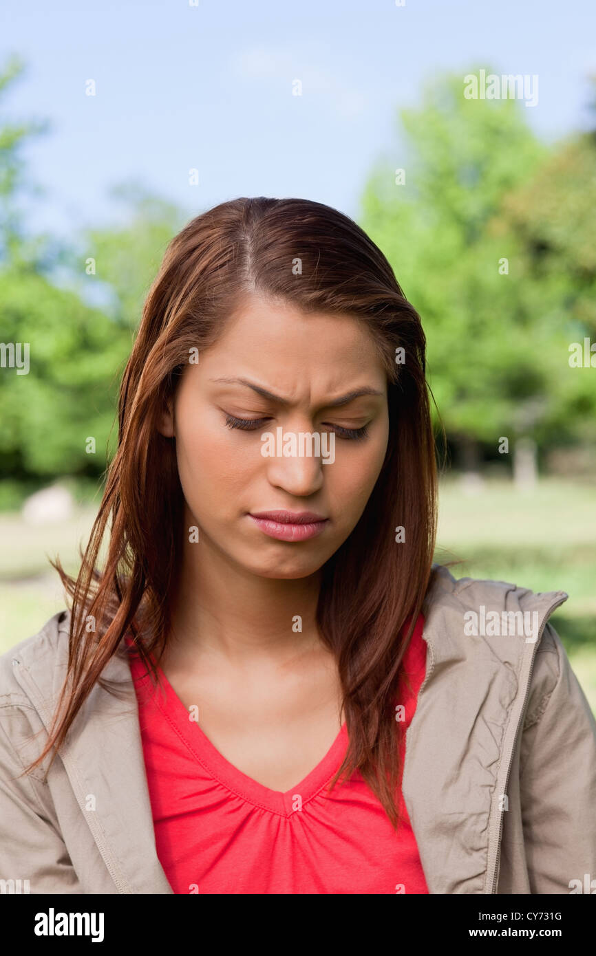 Woman looking downwards with a disappointed expresssion on her face ...