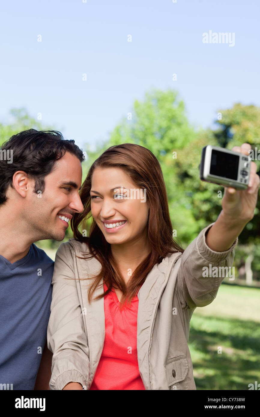 Young woman and her friend look at each other while she takes a photo ...