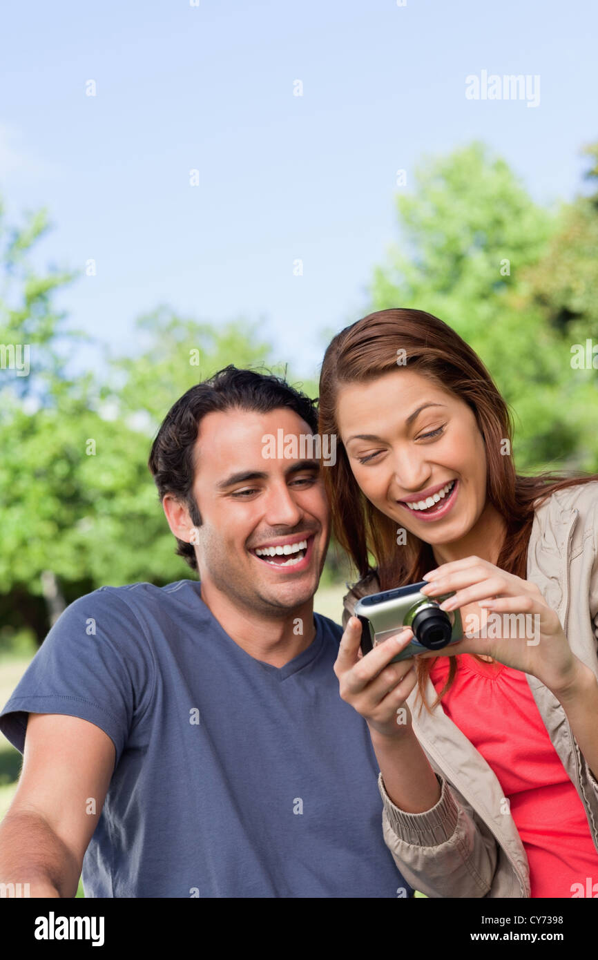 Two friends smiling happily as the look at the photo collection in a ...