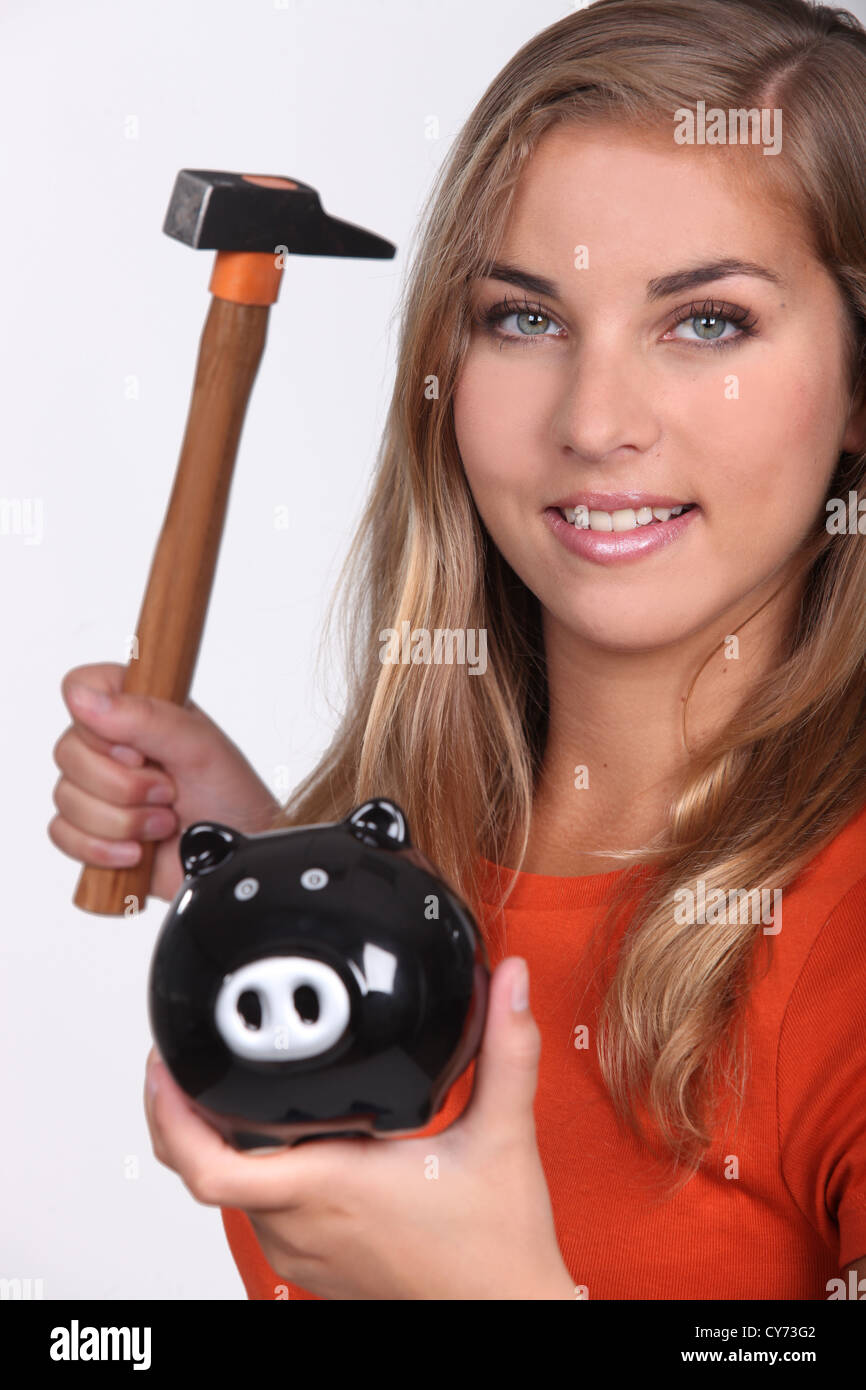 Young woman smashing her piggy bank Stock Photo - Alamy