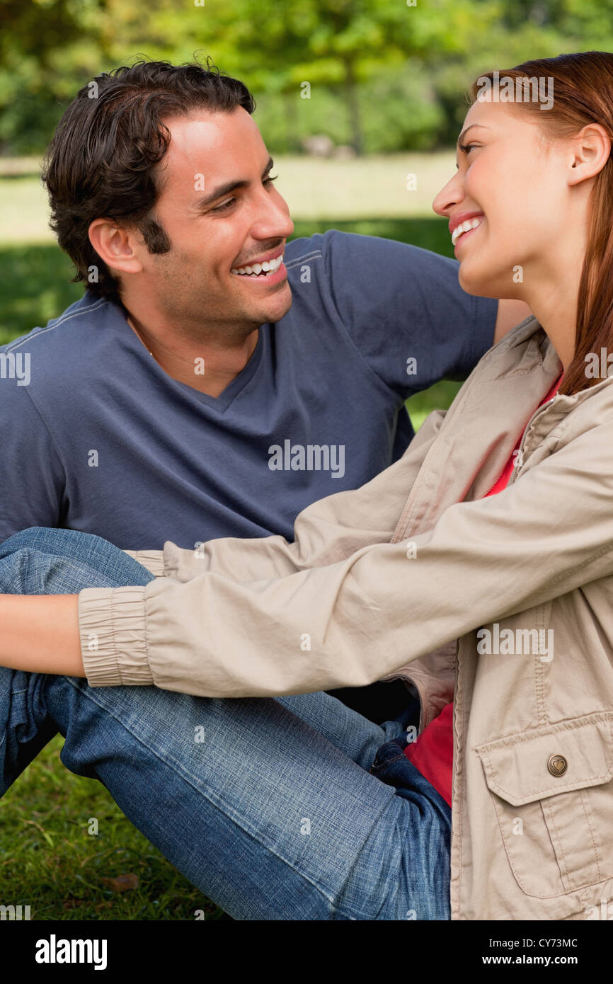 Two friends laughing while they are both sitting on the grass Stock ...