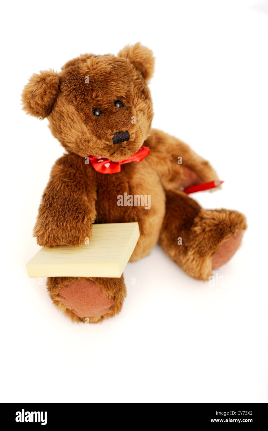 Teddy bear sitting with notes and pencil on white background Stock ...