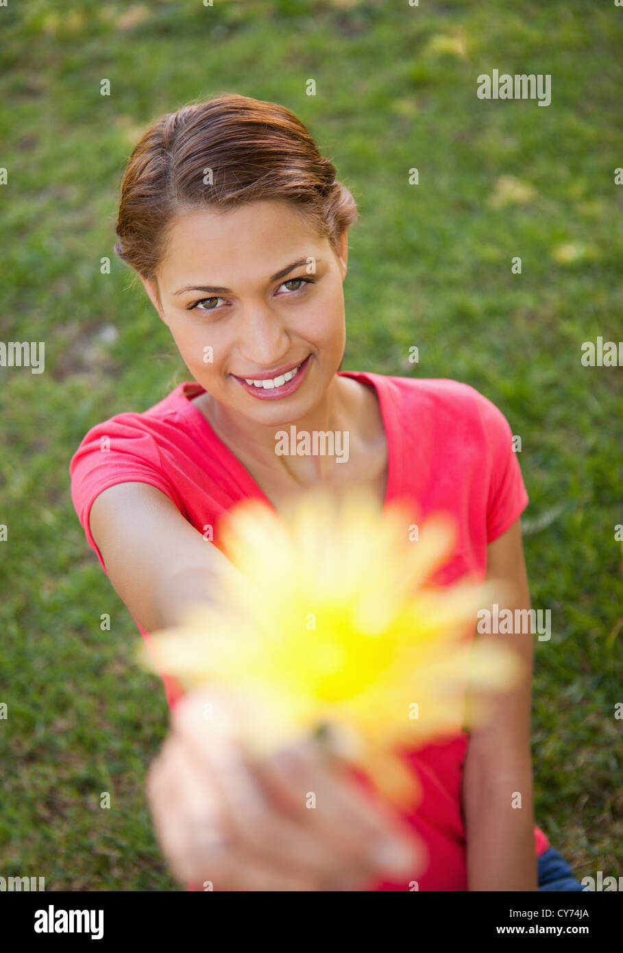 Woman holding a flower in one hand at arms reach Stock Photo - Alamy