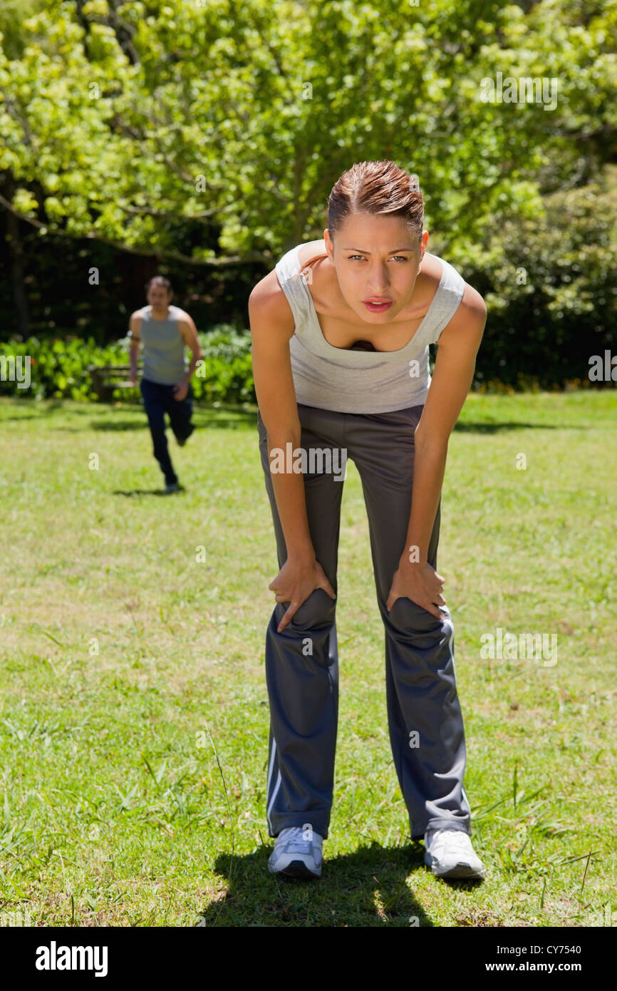 woman bending over while a man is running in the background Stock Photo ...