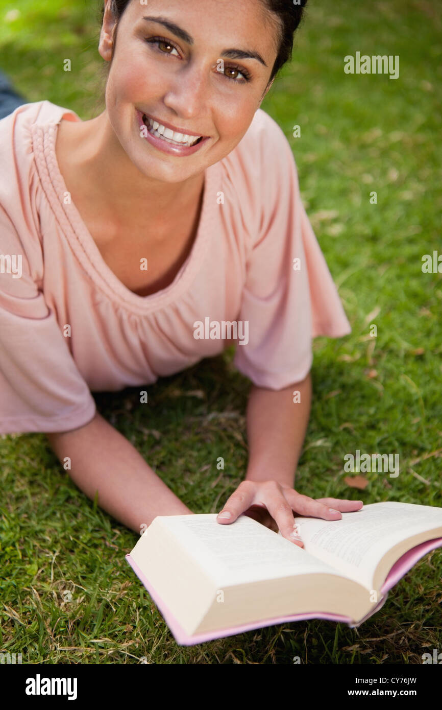 Smiling woman looking up while reading a book as she lies down Stock ...