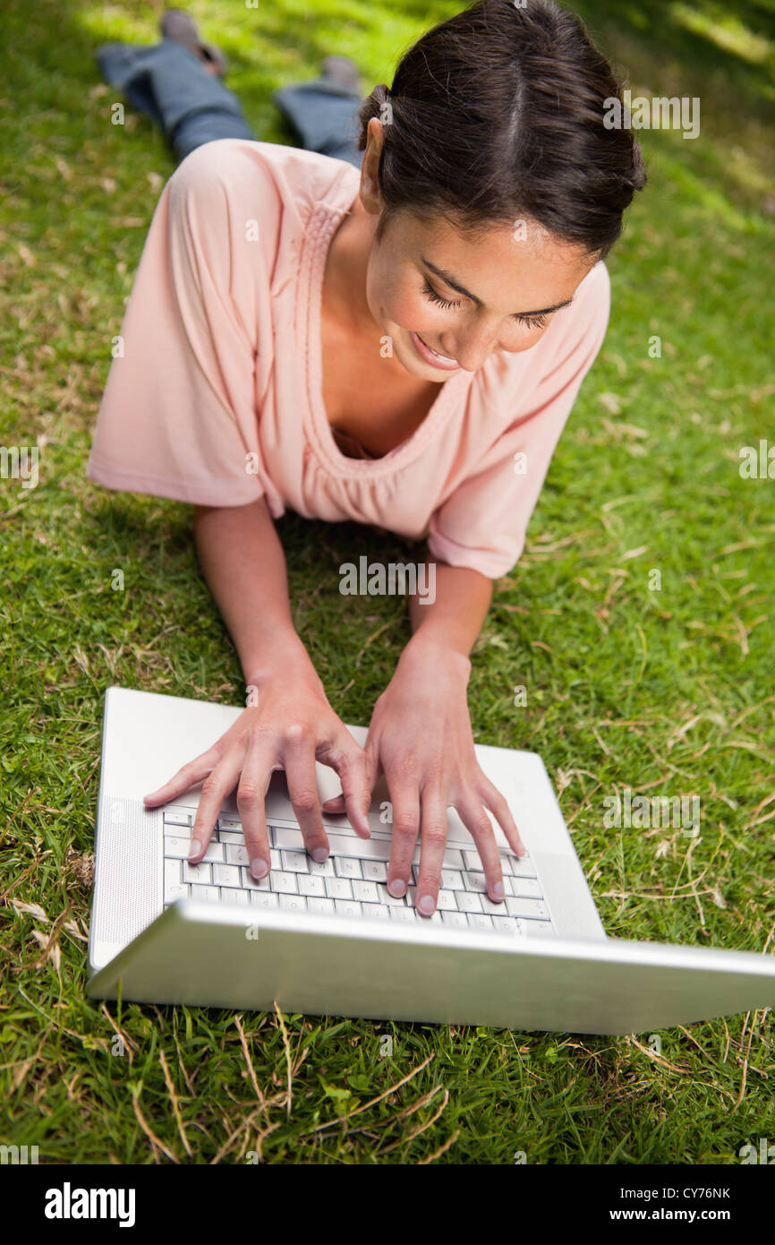 Woman smiling as she uses a laptop while lying down Stock Photo - Alamy