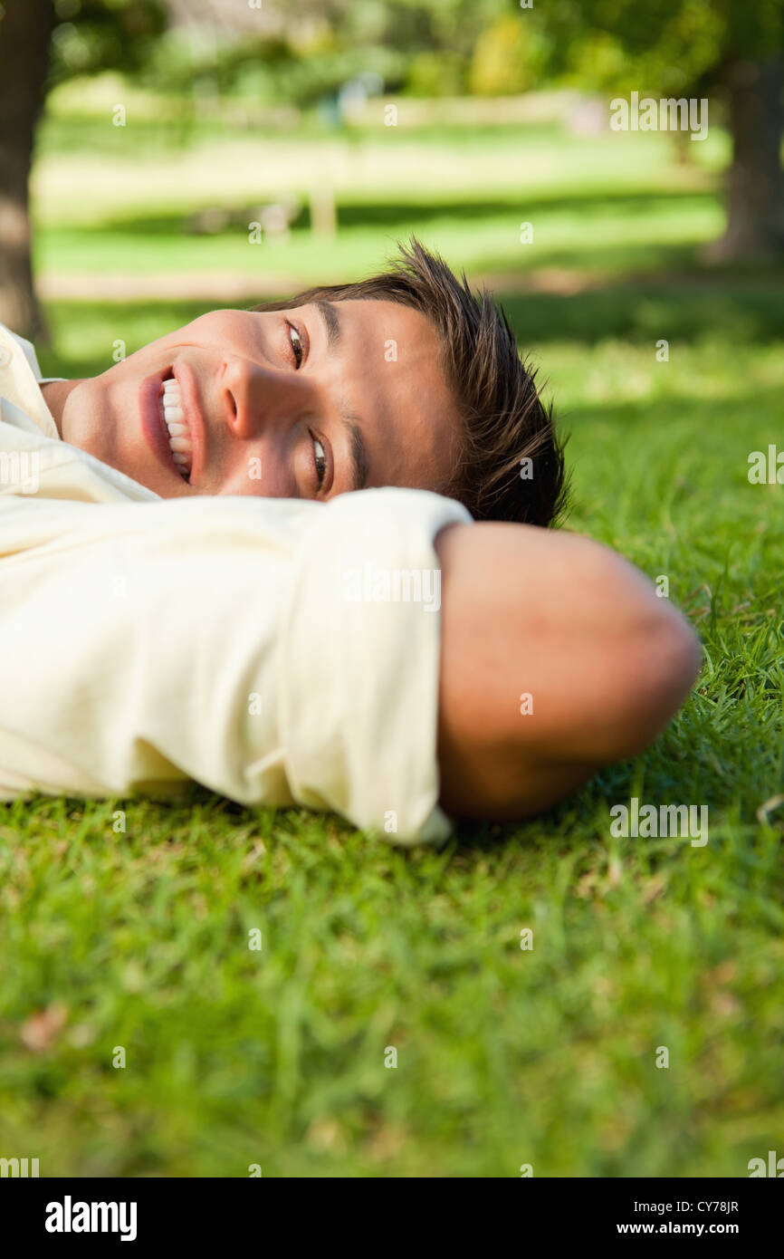 Man smiling while lying with the side of his head resting on his hands ...