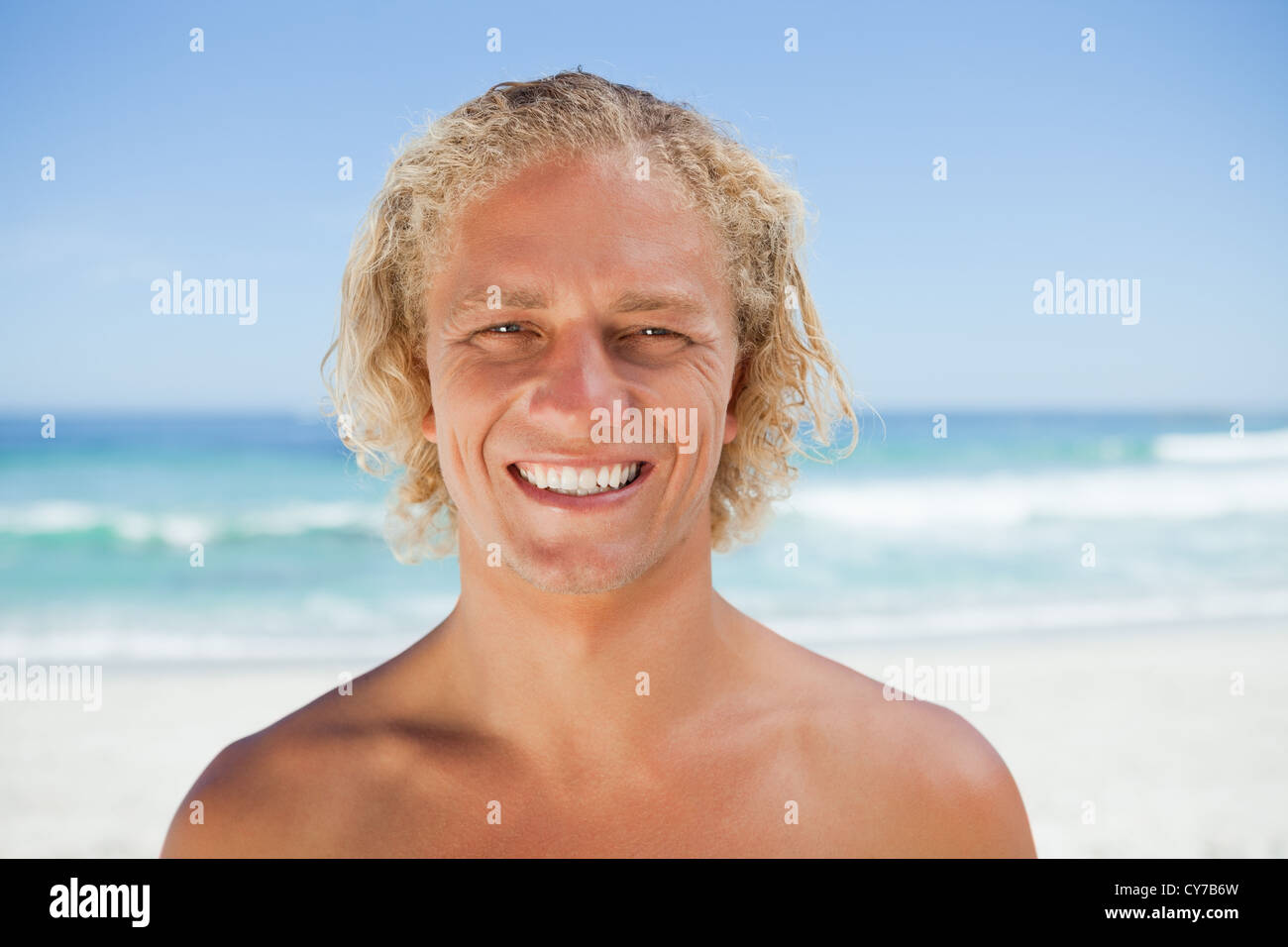 Young smiling man standing on the beach Stock Photo - Alamy