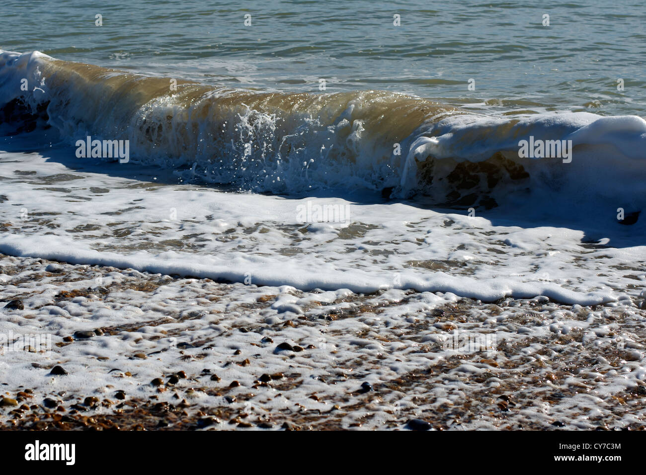 Breaking waves, swash and backwash over shingle on the beach at ...