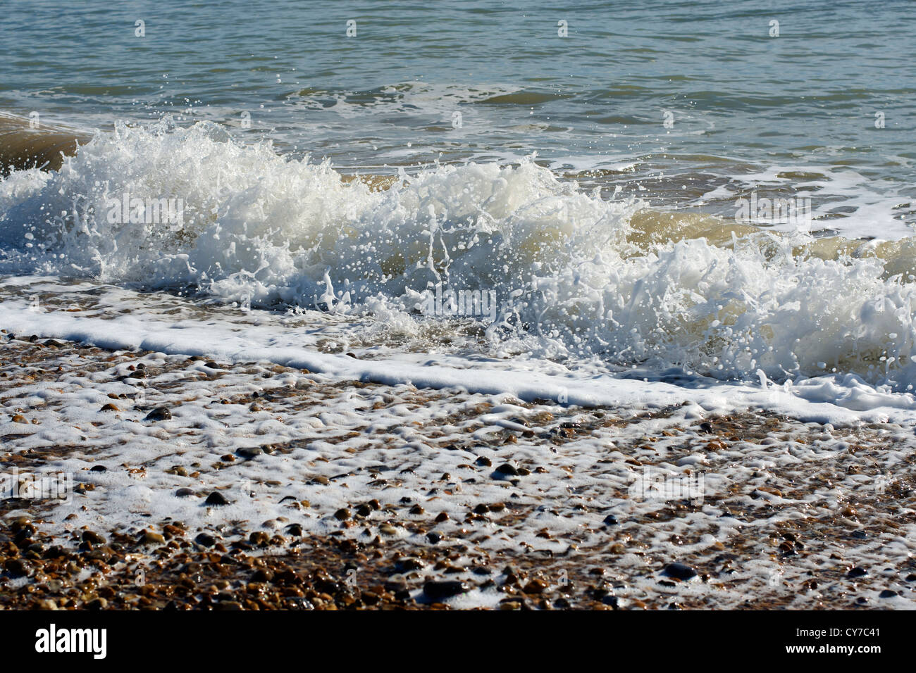 Breaking waves, swash and backwash over shingle on the beach at Stock ...