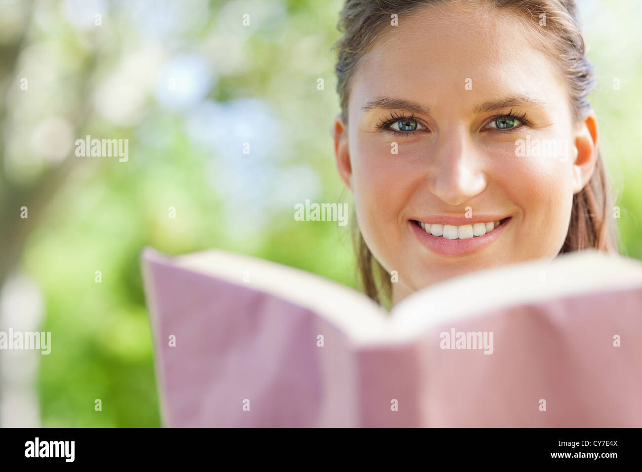 Smiling woman reading a book in the park Stock Photo - Alamy