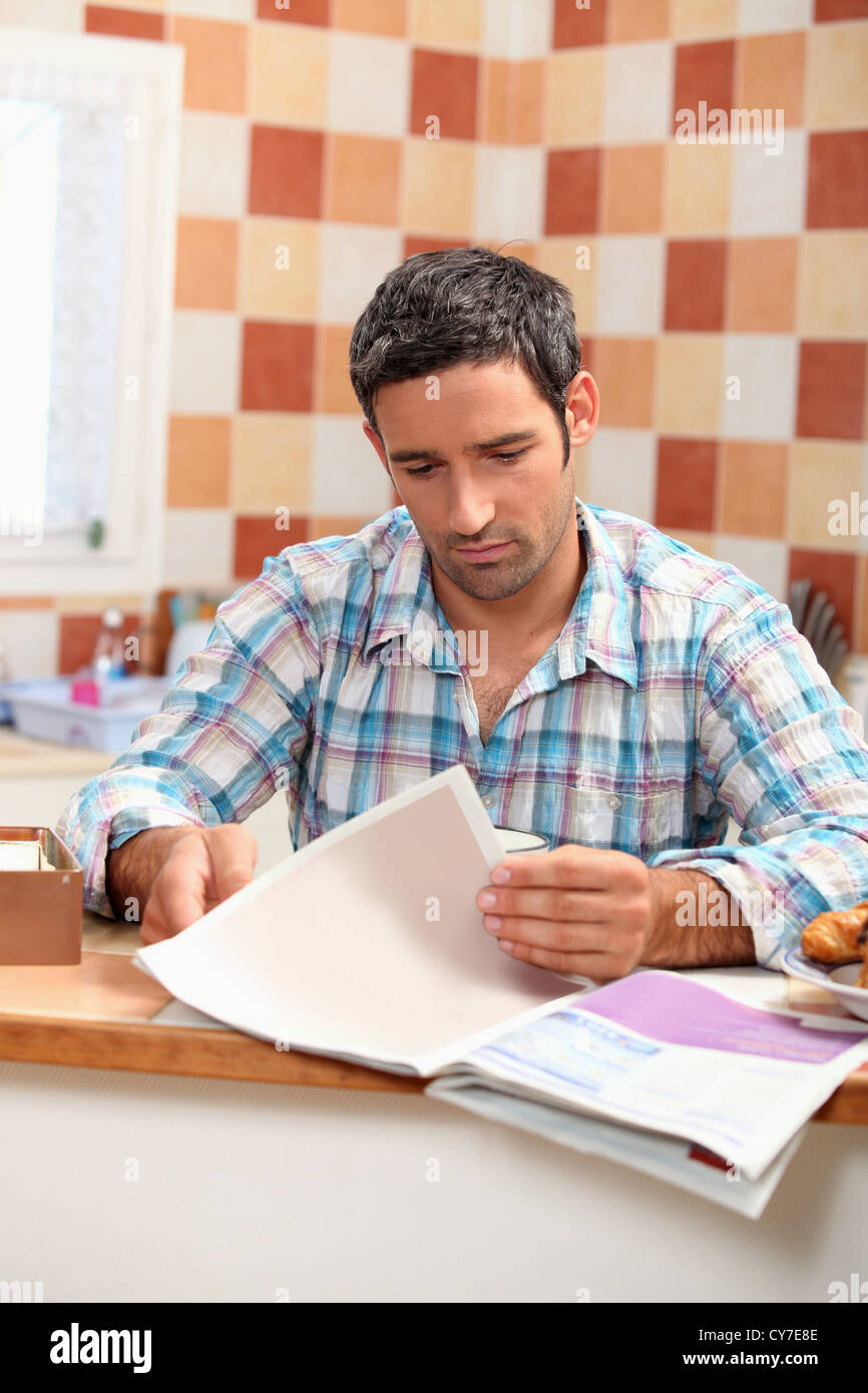 Man reading a brochure at a breakfast bar Stock Photo - Alamy
