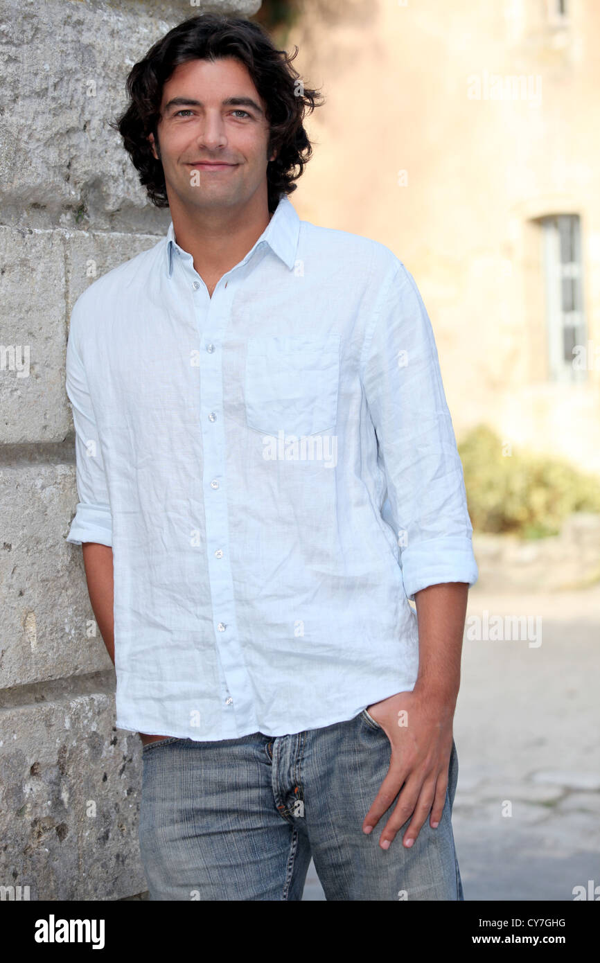 Man casually leaning against stone building Stock Photo - Alamy