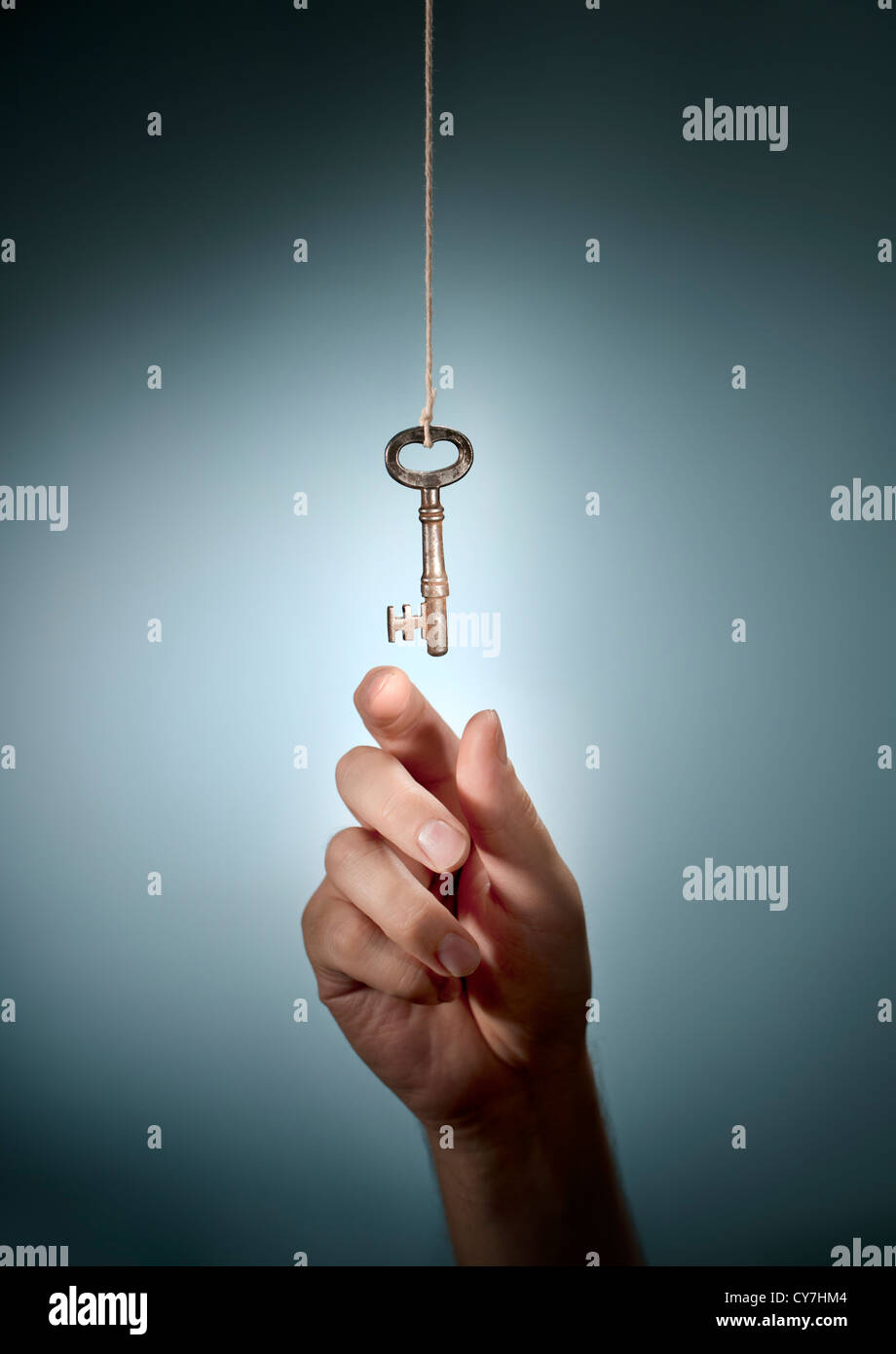 Conceptual image of a hand taking an old key hanging from a string ...