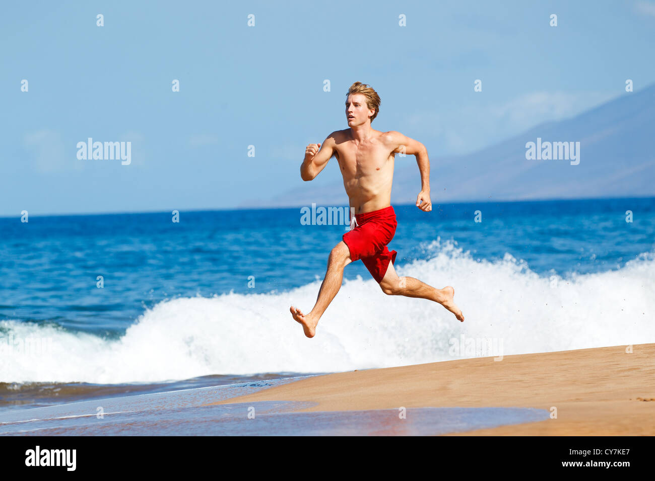 Physically fit man running on Beach Stock Photo - Alamy