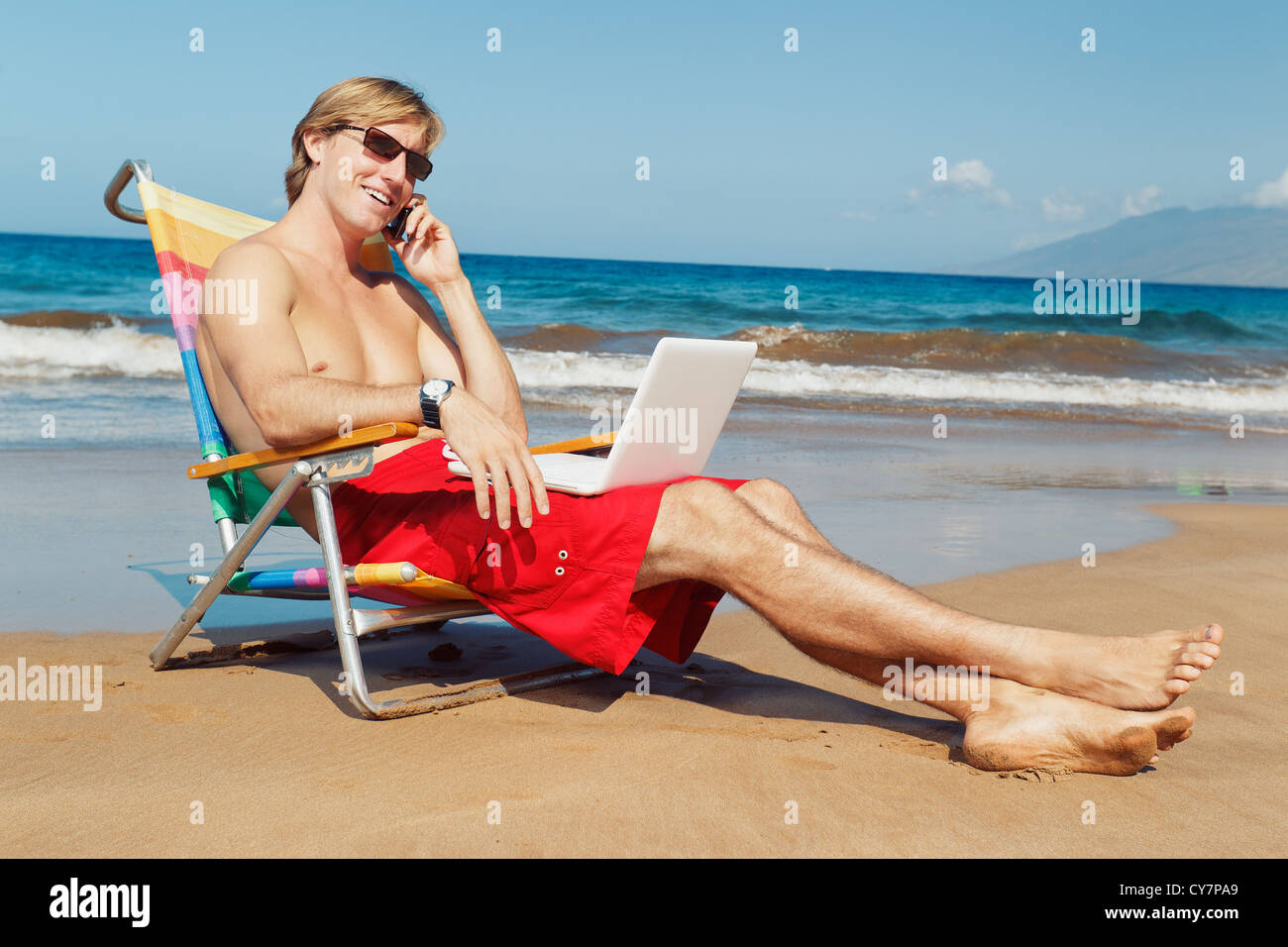 Business man calling by cell phone and working on computer at the beach ...