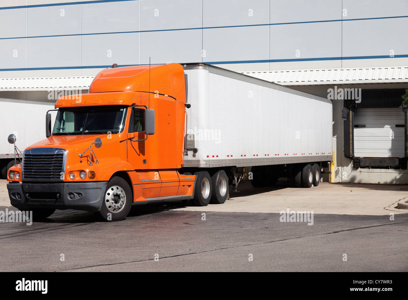 Orange semi truck by the door Stock Photo - Alamy