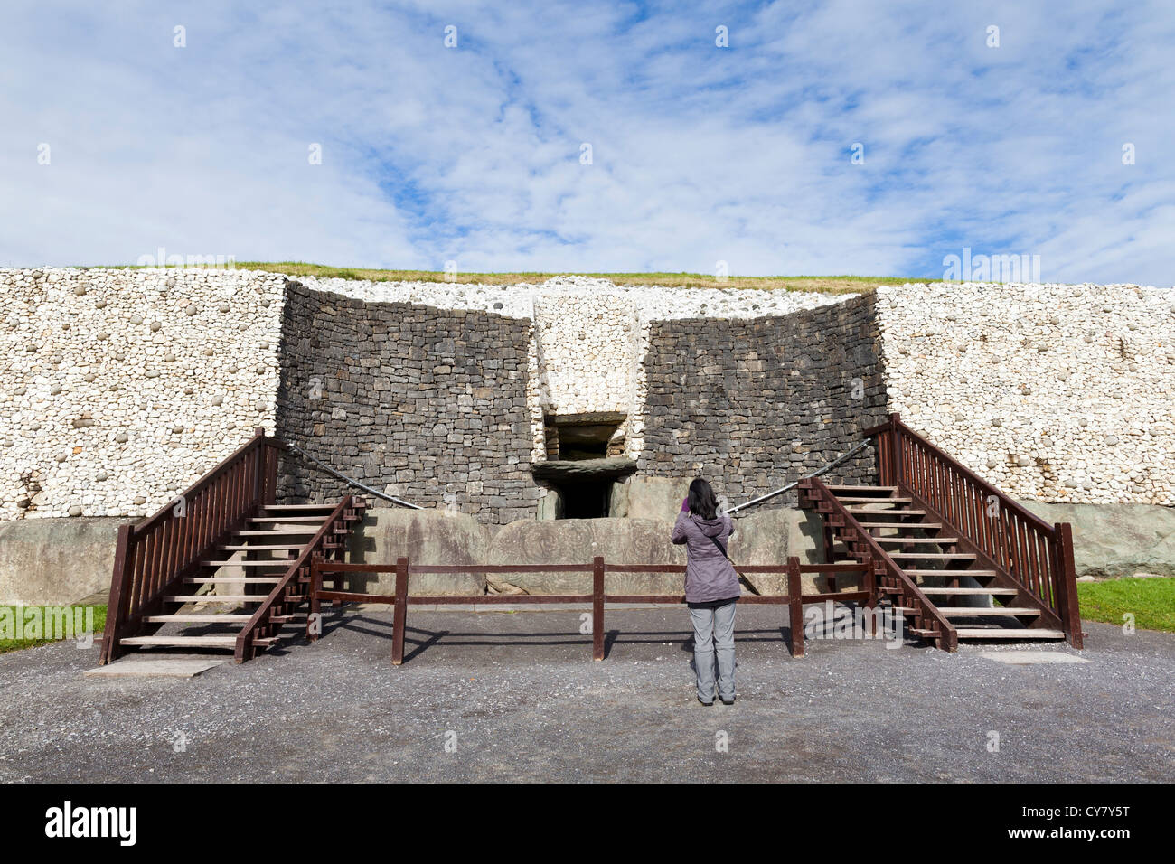 woman visitor photographs the entrance to Newgrange neolithic passage ...