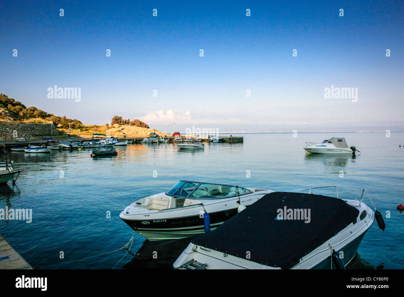 Boats on a flat calm sea in a small village harbor on the island of Krk ...