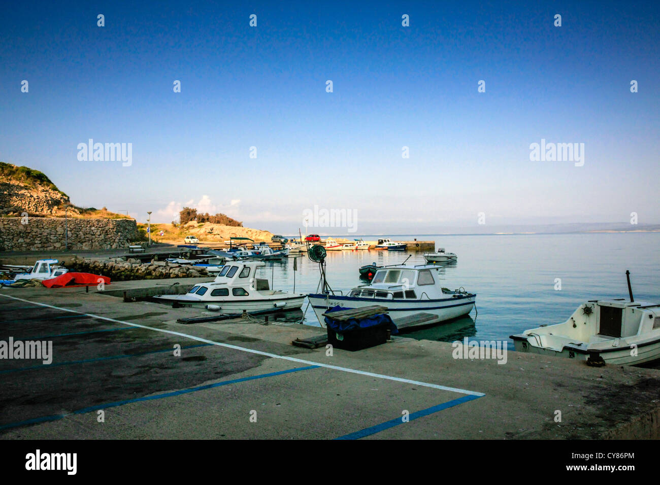 Boats on a flat calm sea in a small village harbor on the island of Krk ...