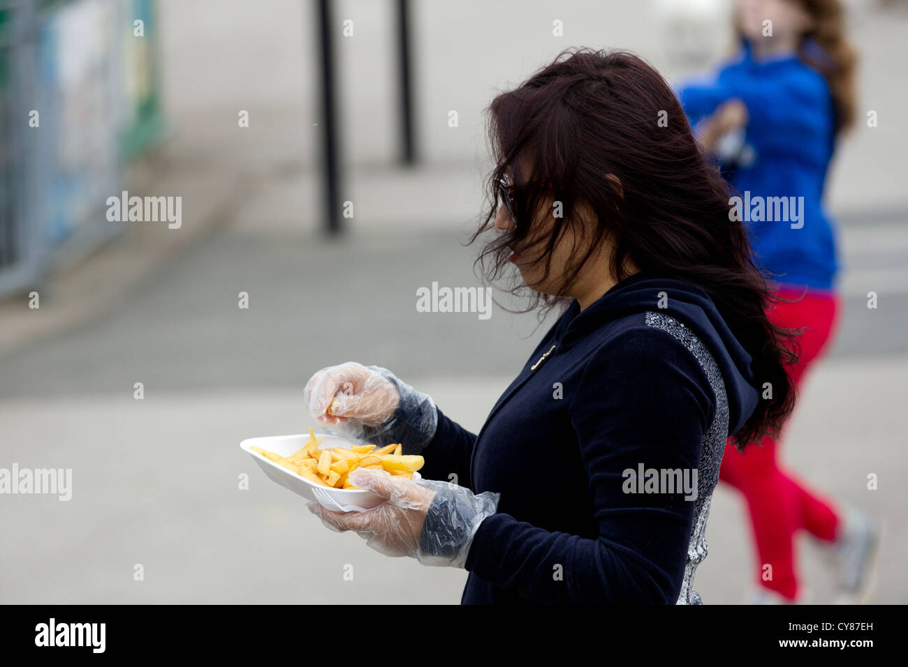 Japanese woman eating with her hygienic plastic gloved hands chips ...