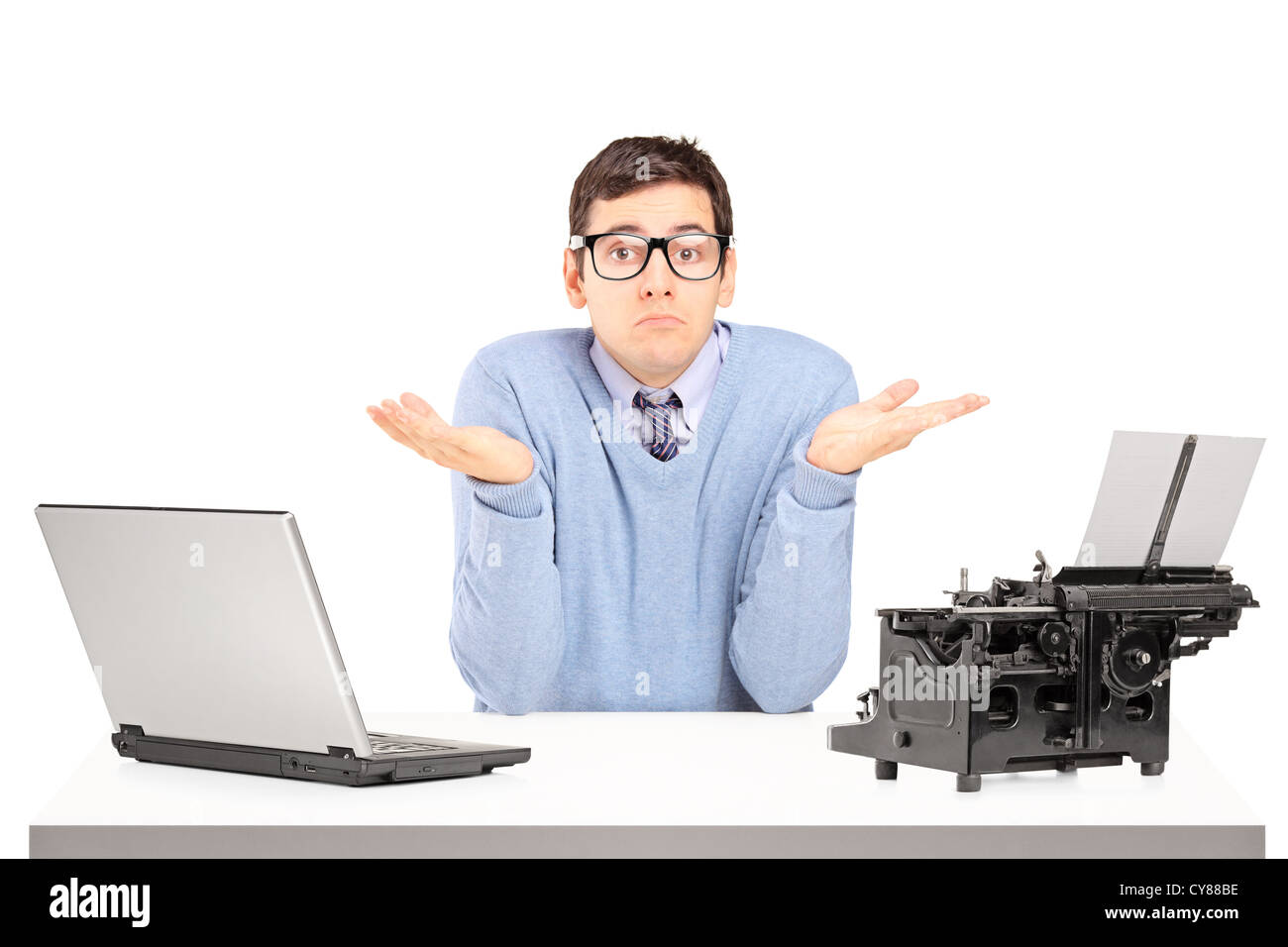 Confused young man with a laptop and typing machine on a table isolated ...