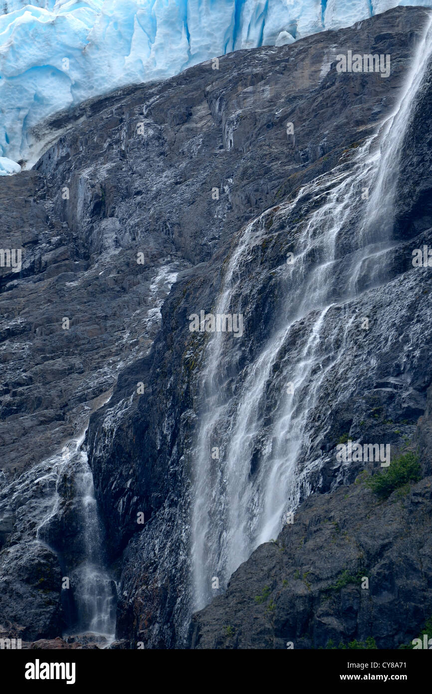 A hanging glacier ice with melt water spilling down the bare rocks ...