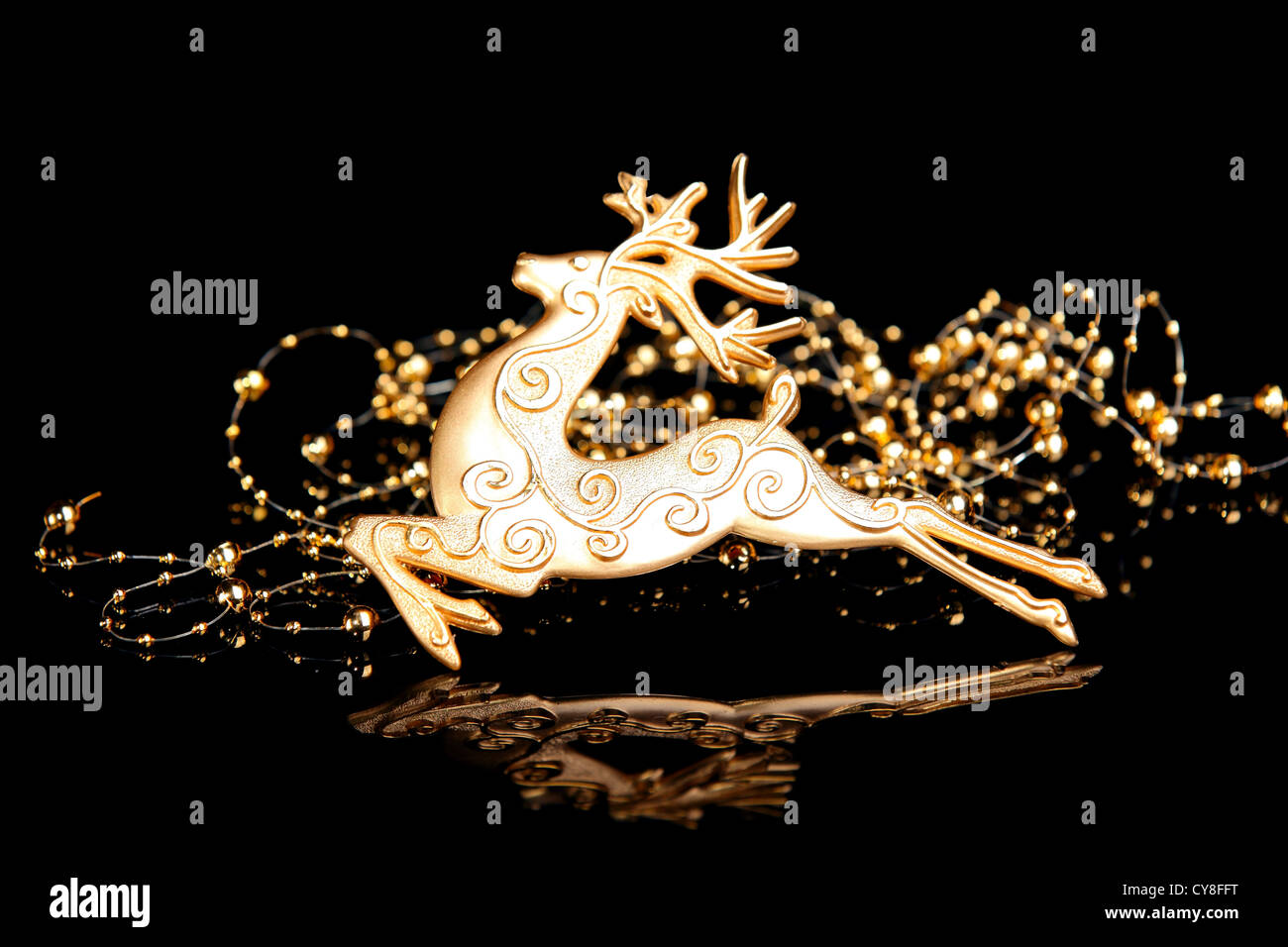 Gold deer with beads on black background Stock Photo - Alamy