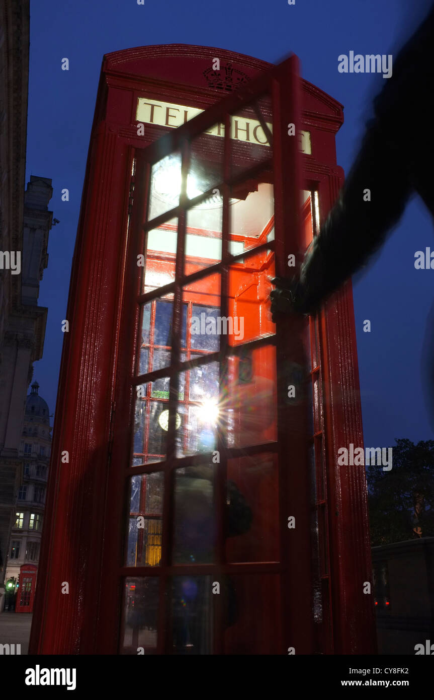 Person entering red telephone box at night Stock Photo - Alamy