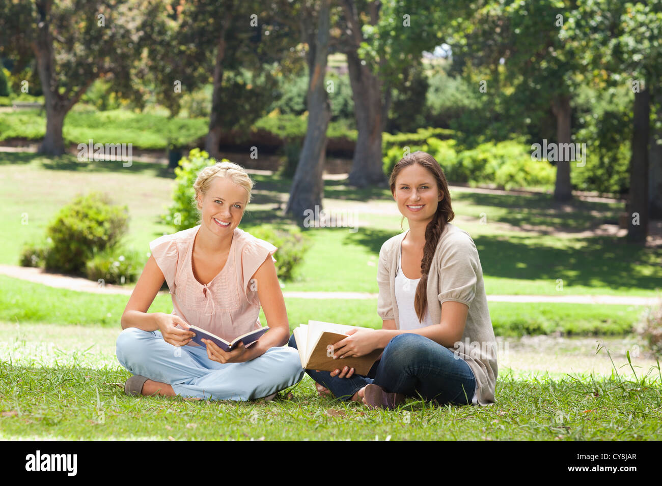 Friends sitting with their books in the park Stock Photo - Alamy