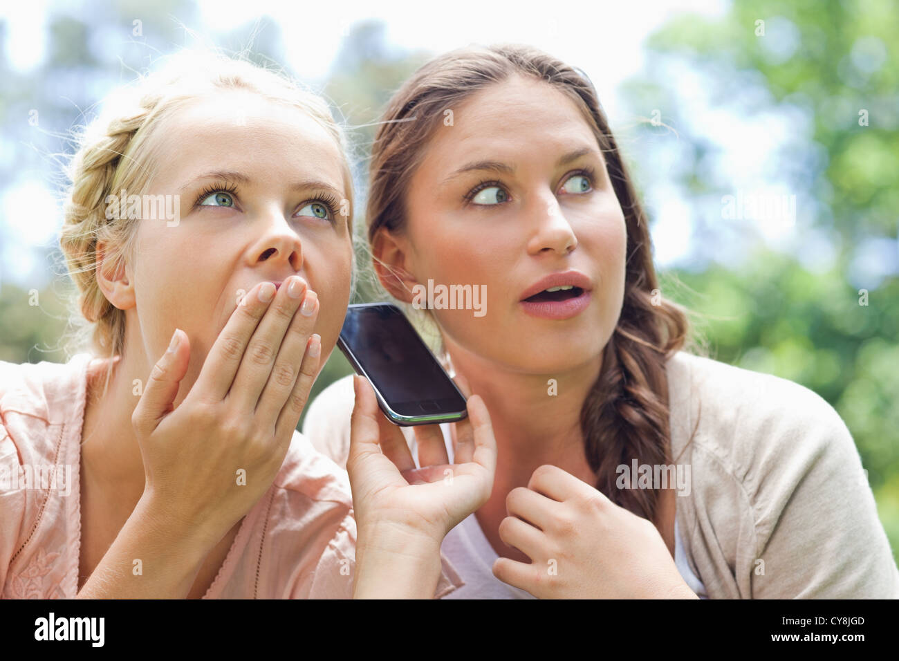 Friends listening to a phone call in the park Stock Photo - Alamy