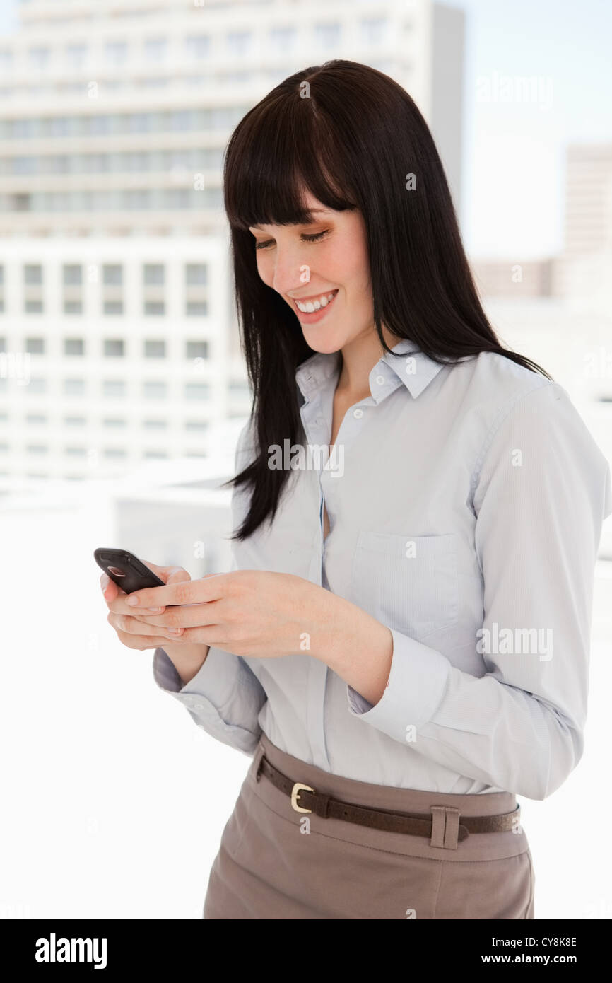 Smiling woman at work sending a text message Stock Photo - Alamy