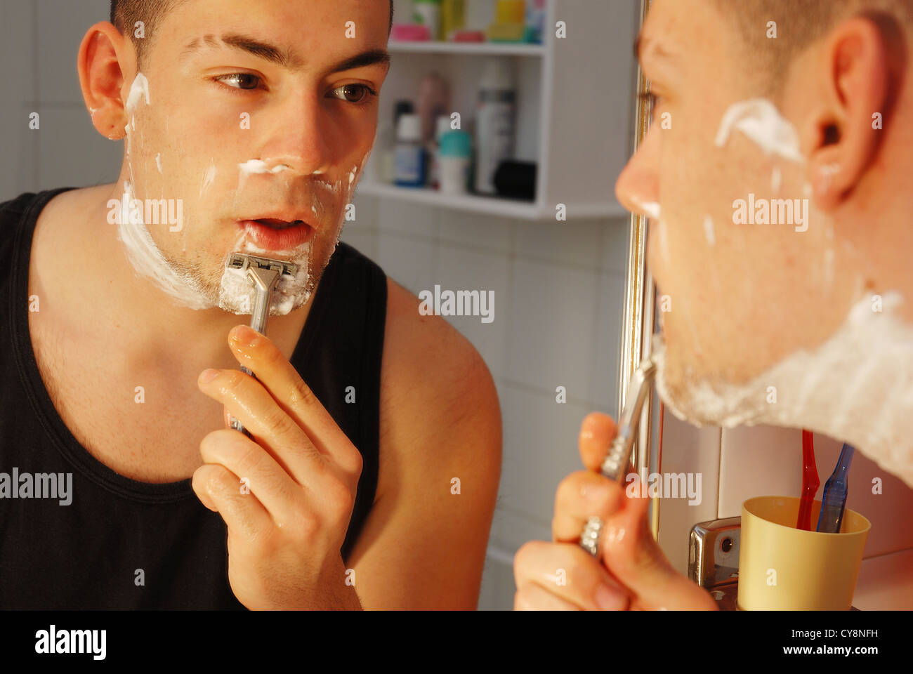 Young Man Shaving His Beard In Front Of The Mirror Close View Stock