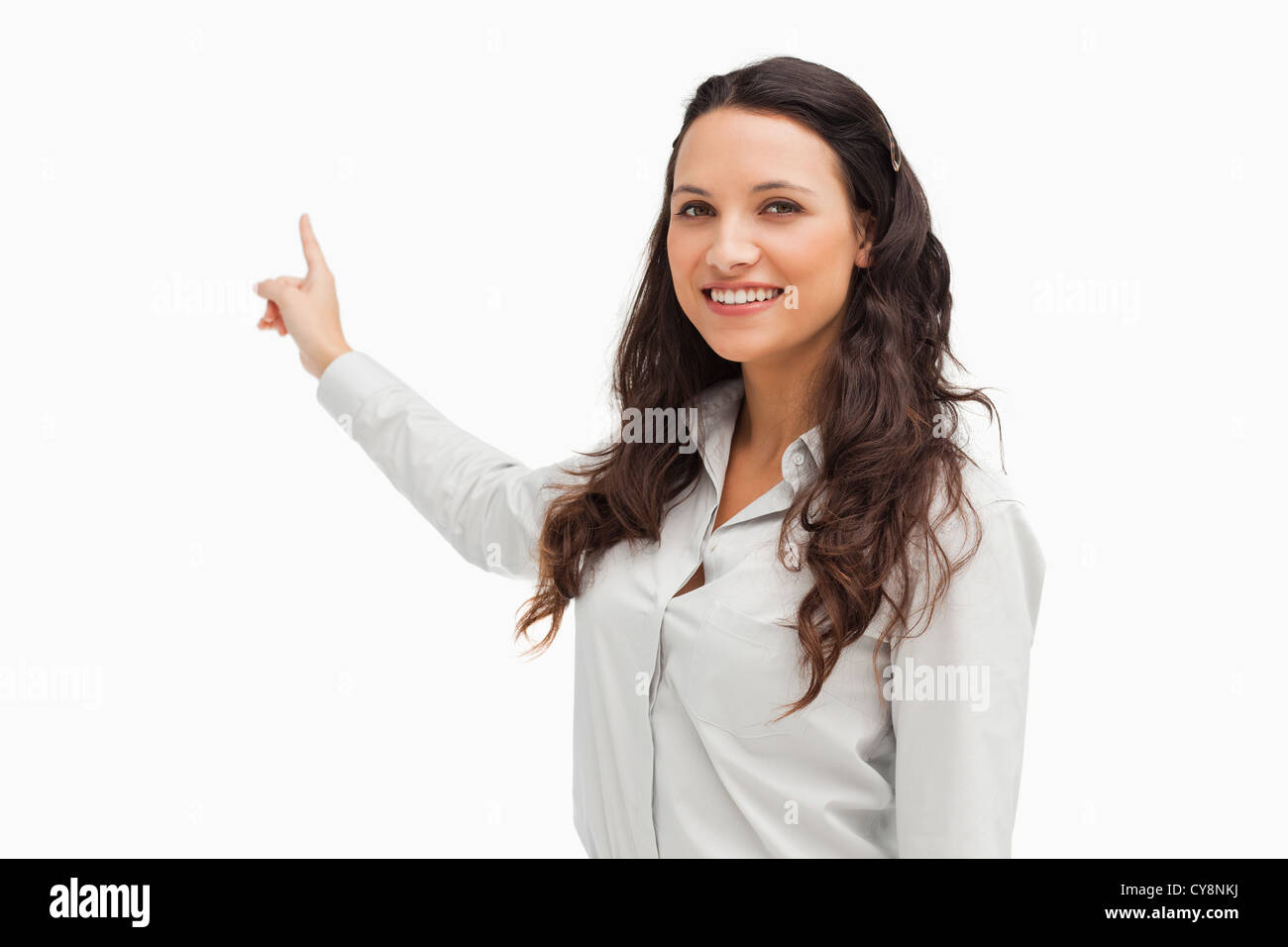 Portrait of a smiling brunette pointing behind her Stock Photo - Alamy