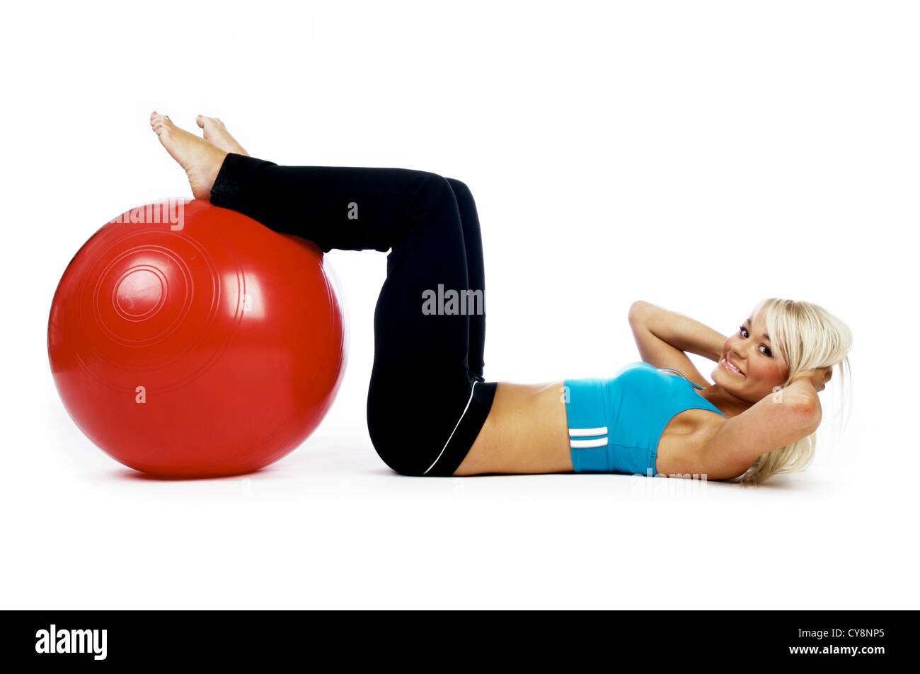 Young blonde woman working out on a red fitness ball isolated on a ...