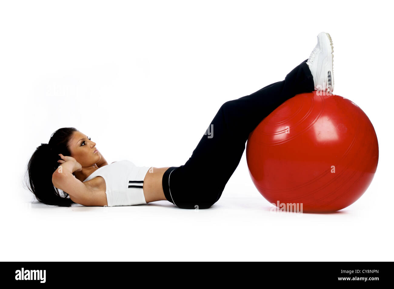 Young brunette woman working out on a red fitness ball isolated on a ...