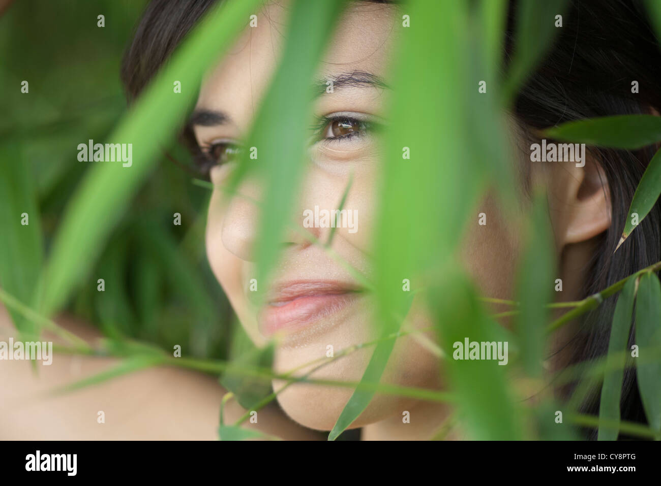 Young woman behind foliage, portrait Stock Photo - Alamy