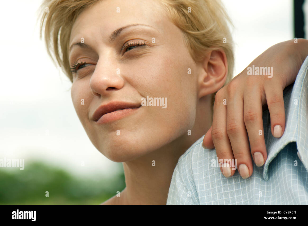 Young woman with hand on man's shoulder, looking away and smiling Stock ...