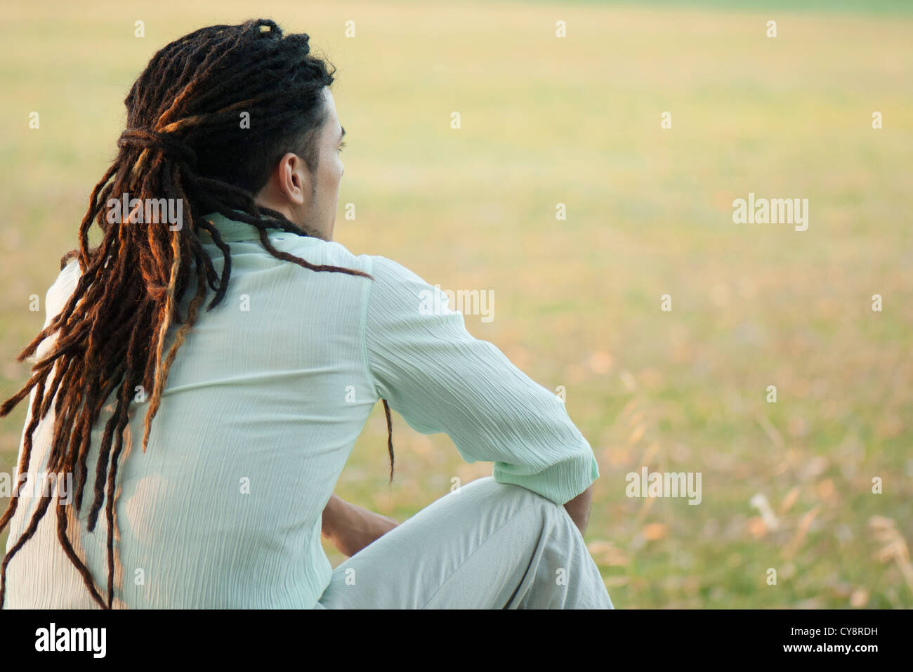 Man with dreadlocks sitting outdoors, rear view Stock Photo - Alamy