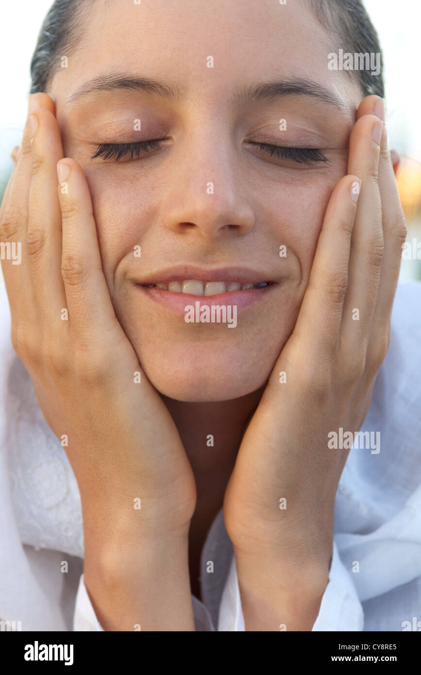 Young woman with hands on face and eyes closed, portrait Stock Photo ...