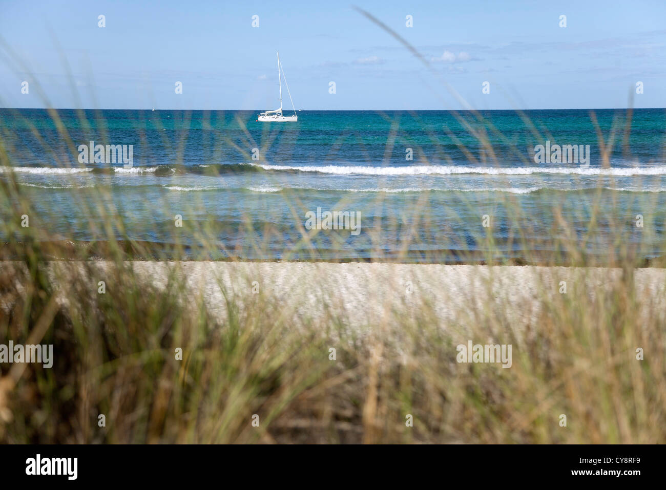 Tranquil beach scene, sail boat visible in distance Stock Photo - Alamy