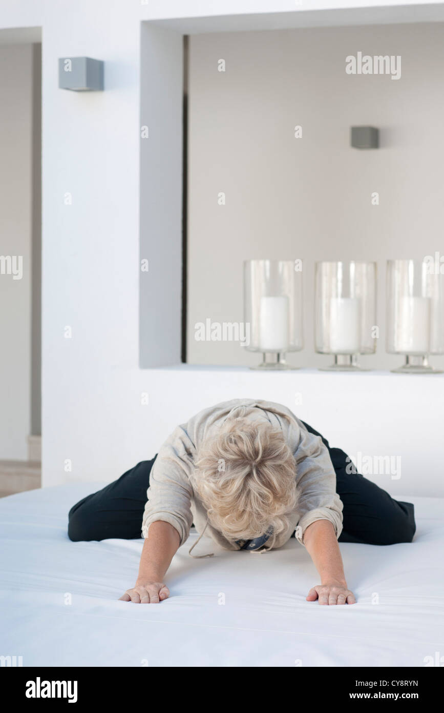 Woman kneeling on bed, leaning forward Stock Photo - Alamy