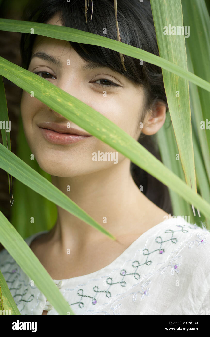 Young woman looking through foliage, portrait Stock Photo - Alamy