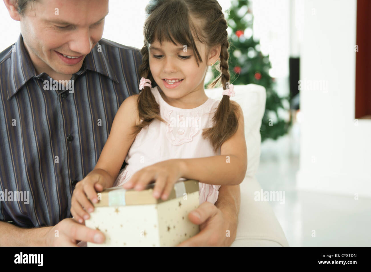 Little girl opening Christmas present with father Stock Photo - Alamy