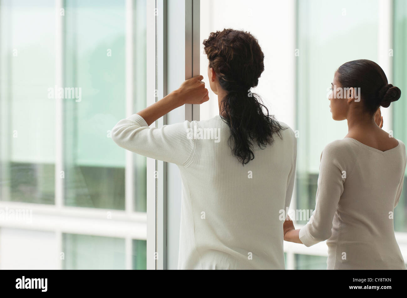 Colleagues standing side by side looking out of window, rear view Stock ...