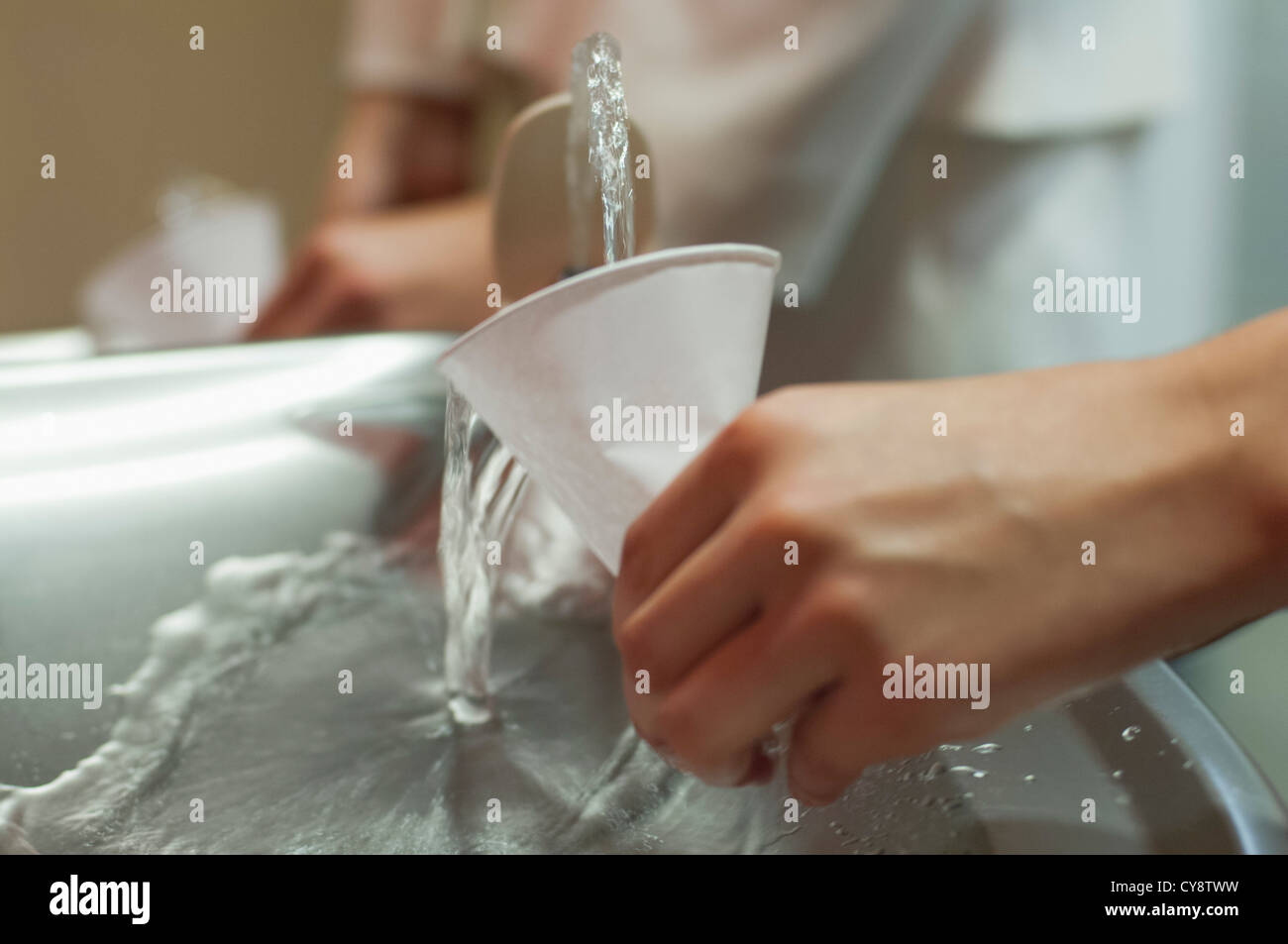Filling cup at drinking fountain, cropped Stock Photo - Alamy