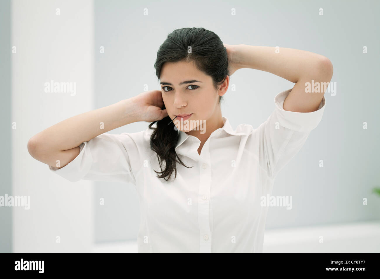 Young woman fixing hair, holding hairpin in mouth Stock Photo - Alamy