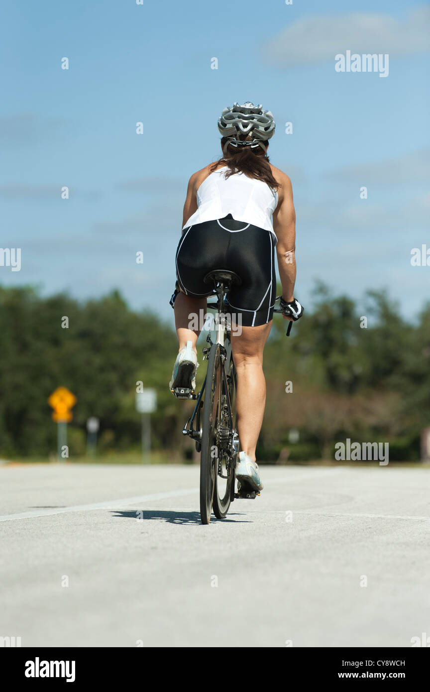 Female cyclist cycling on road Stock Photo - Alamy