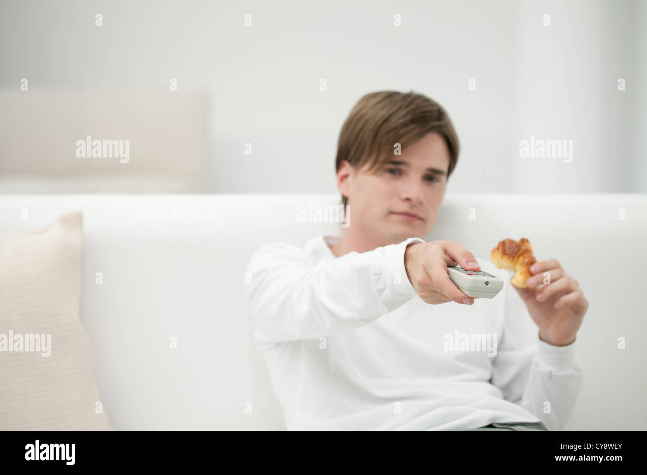 Young man watching TV, changing channel with remote control Stock Photo ...