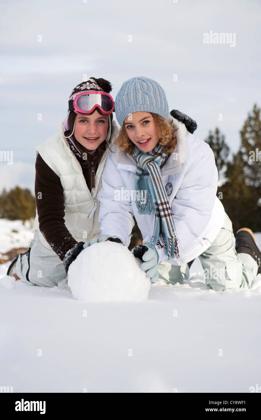 Teenage girls rolling snowball together, portrait Stock Photo - Alamy
